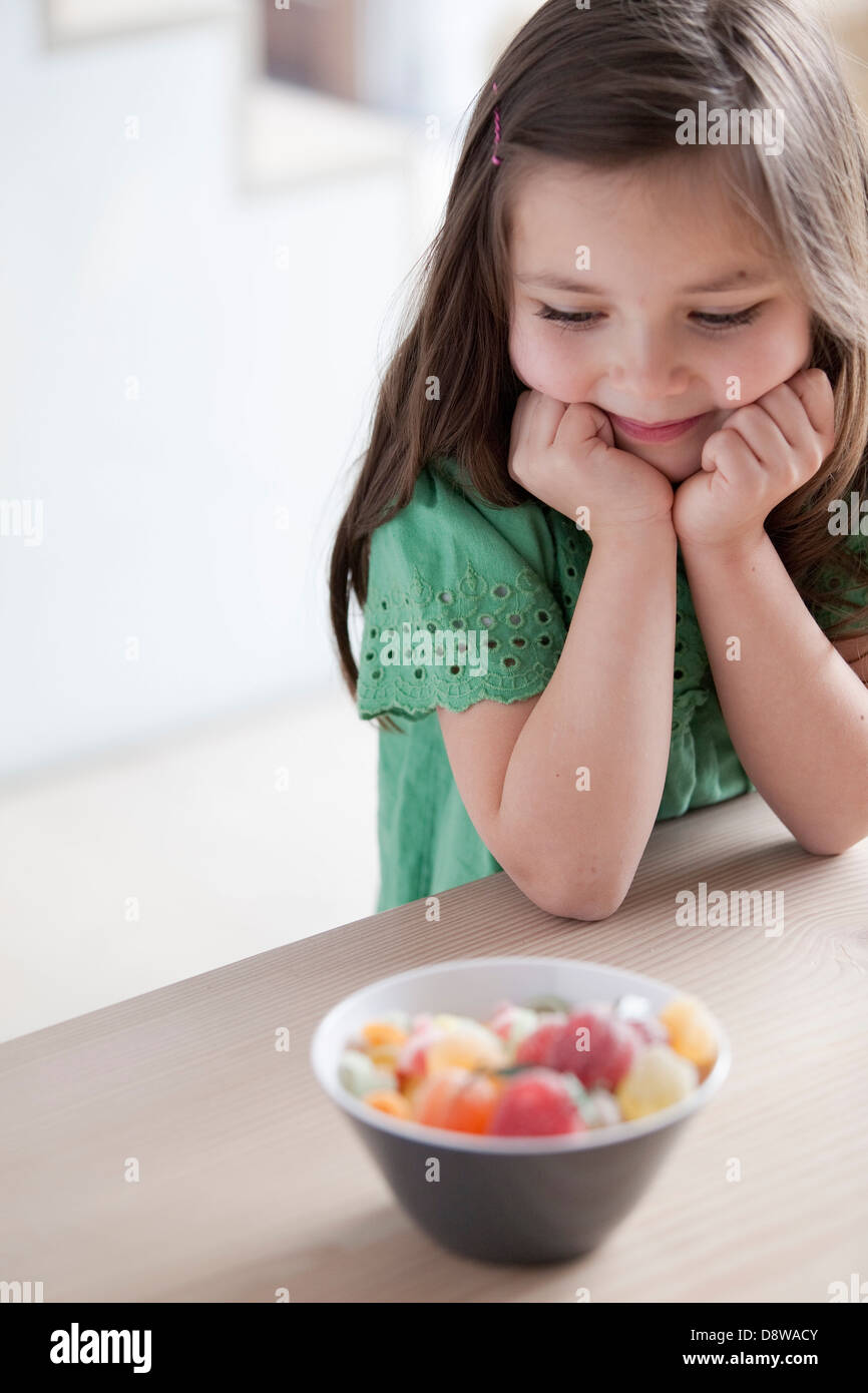 Young girl looking with envy at a bowl of candies Stock Photo - Alamy