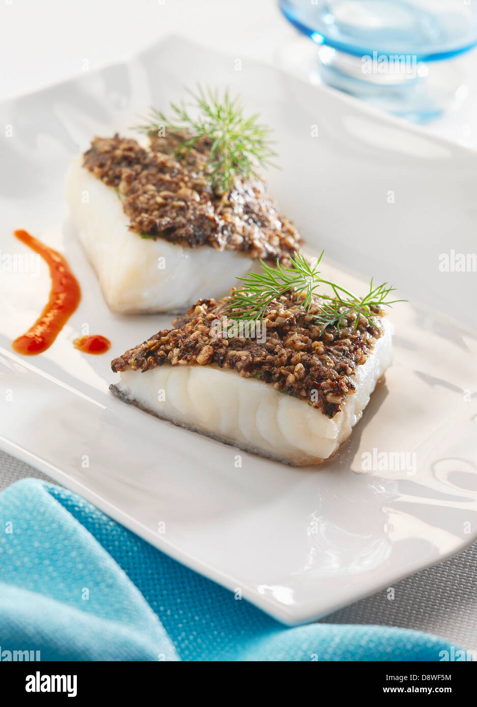 Thick pieces of cod with black olive and pine nut crust Stock Photo - Alamy