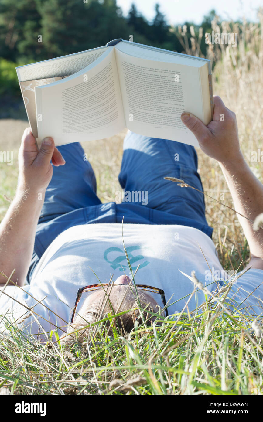 Man lying on meadow and reading book Stock Photo - Alamy