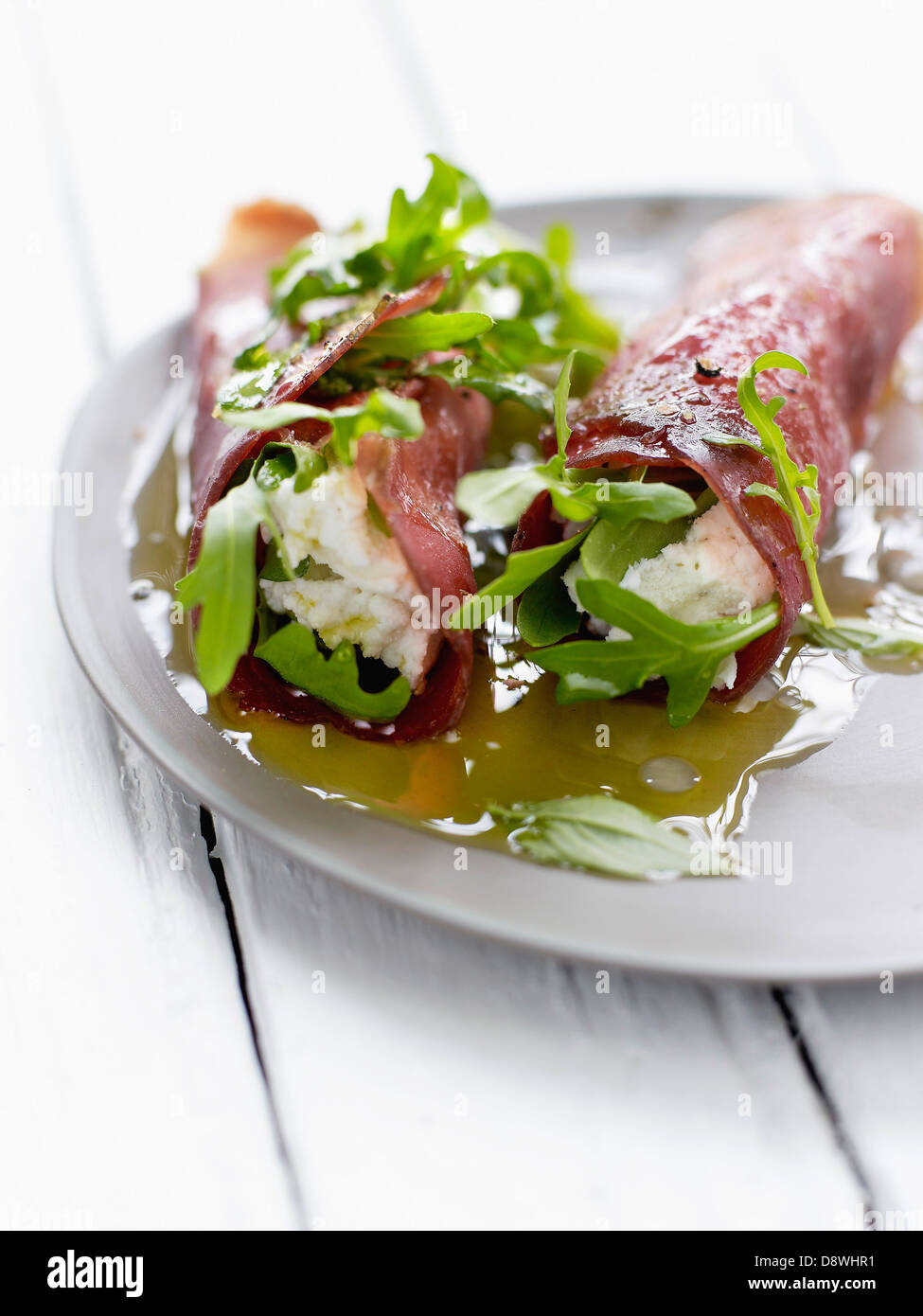 Bresaola rolls stuffed with rocket lettuce,cheese and basil Stock Photo ...