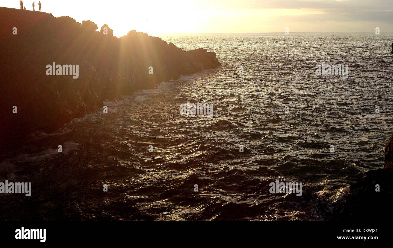 Sun coming over rocky outcrop Stock Photo - Alamy