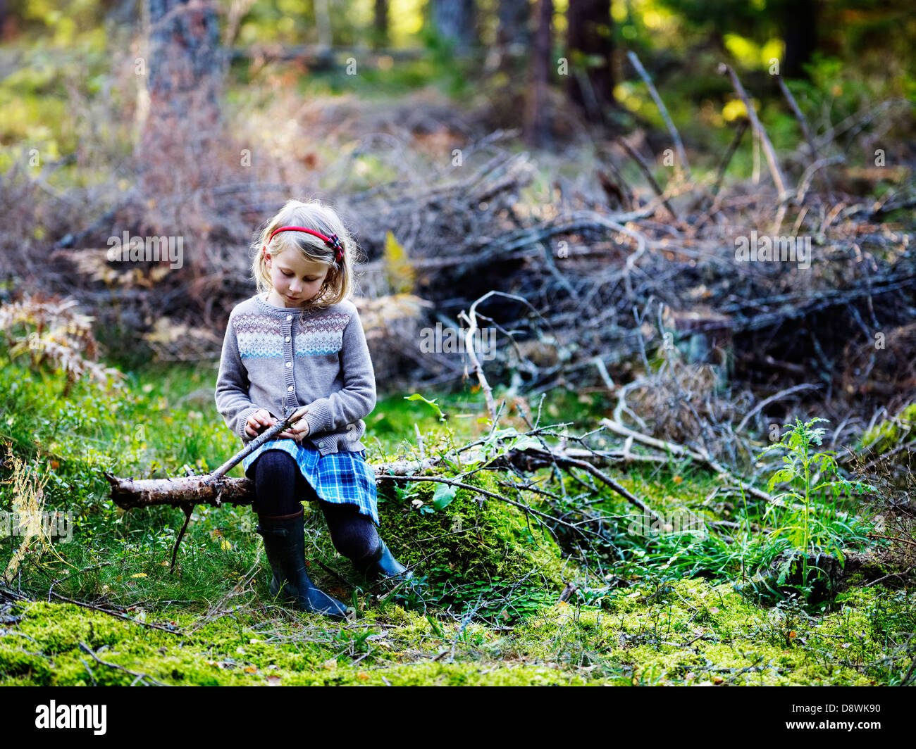 Girl sitting on log in forest Stock Photo - Alamy