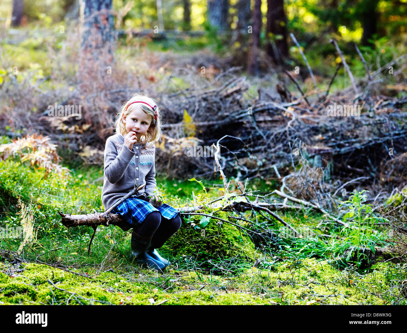 Girl sitting on log in forest Stock Photo - Alamy