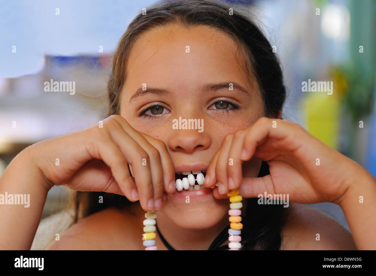 Young girl eating a candy neckless Stock Photo - Alamy