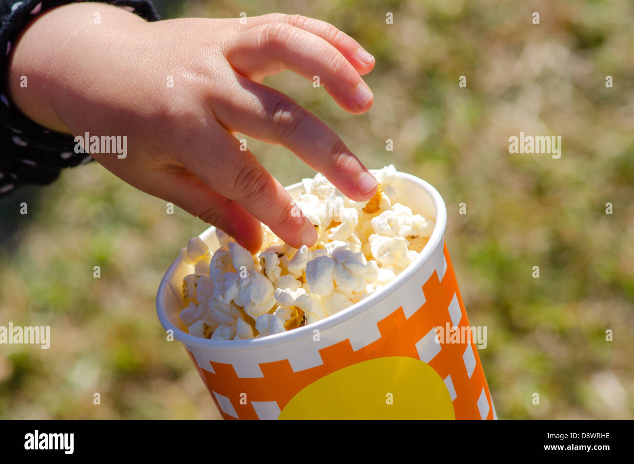 Close-up of child's hand taking popcorn from a cup Stock Photo - Alamy