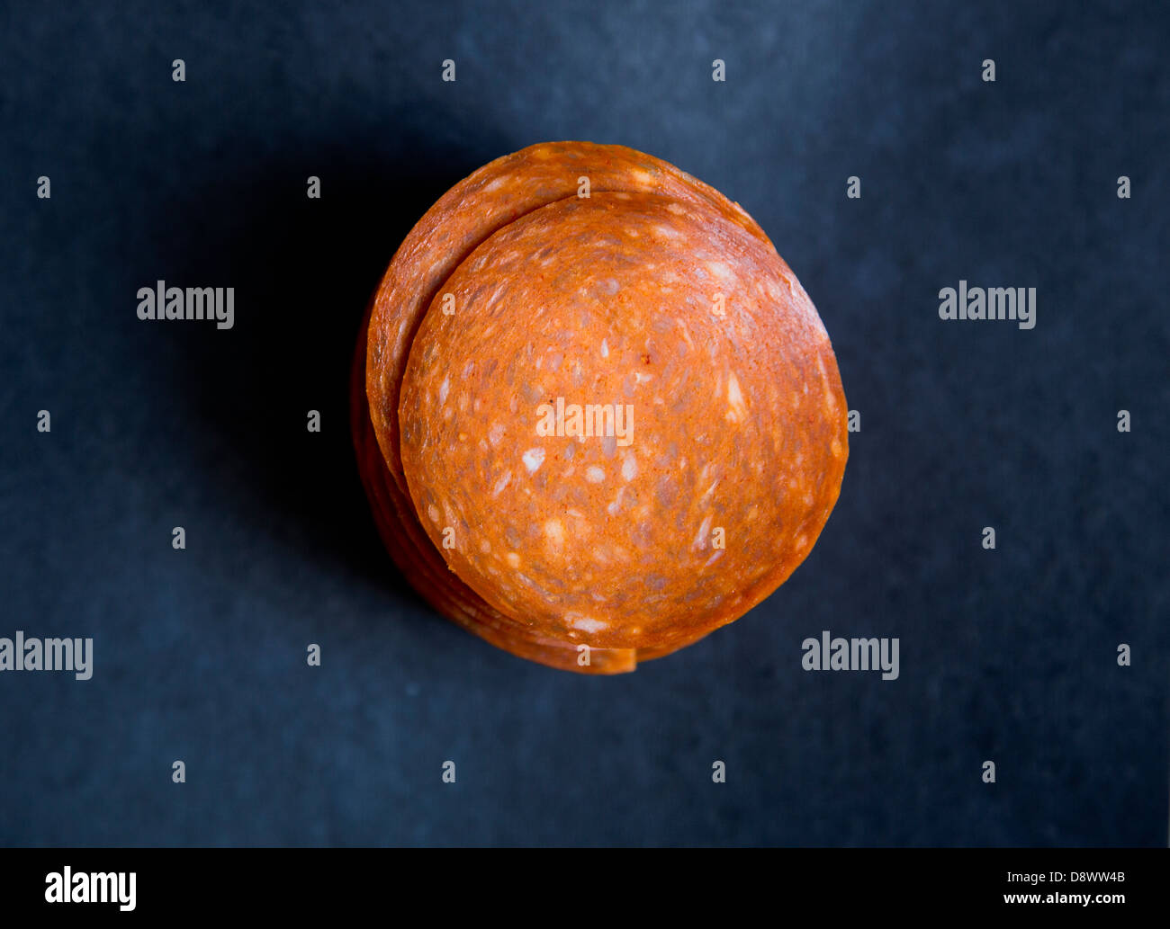 Still life, close up of a stack of pepperoni slices on dark black ...