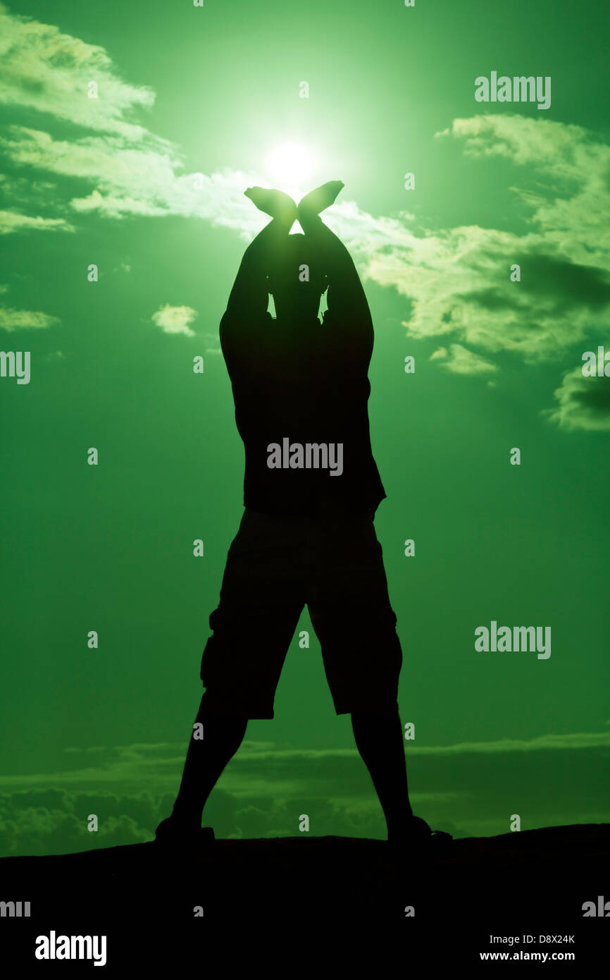 Silhouette of male holding the sun above his head Stock Photo - Alamy