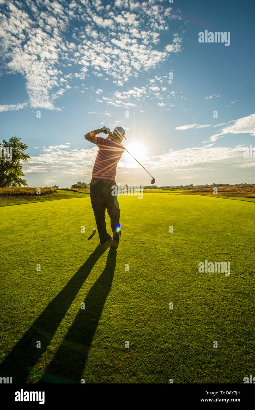 Golfer at tee swinging into the rising sun on the golf course Stock ...