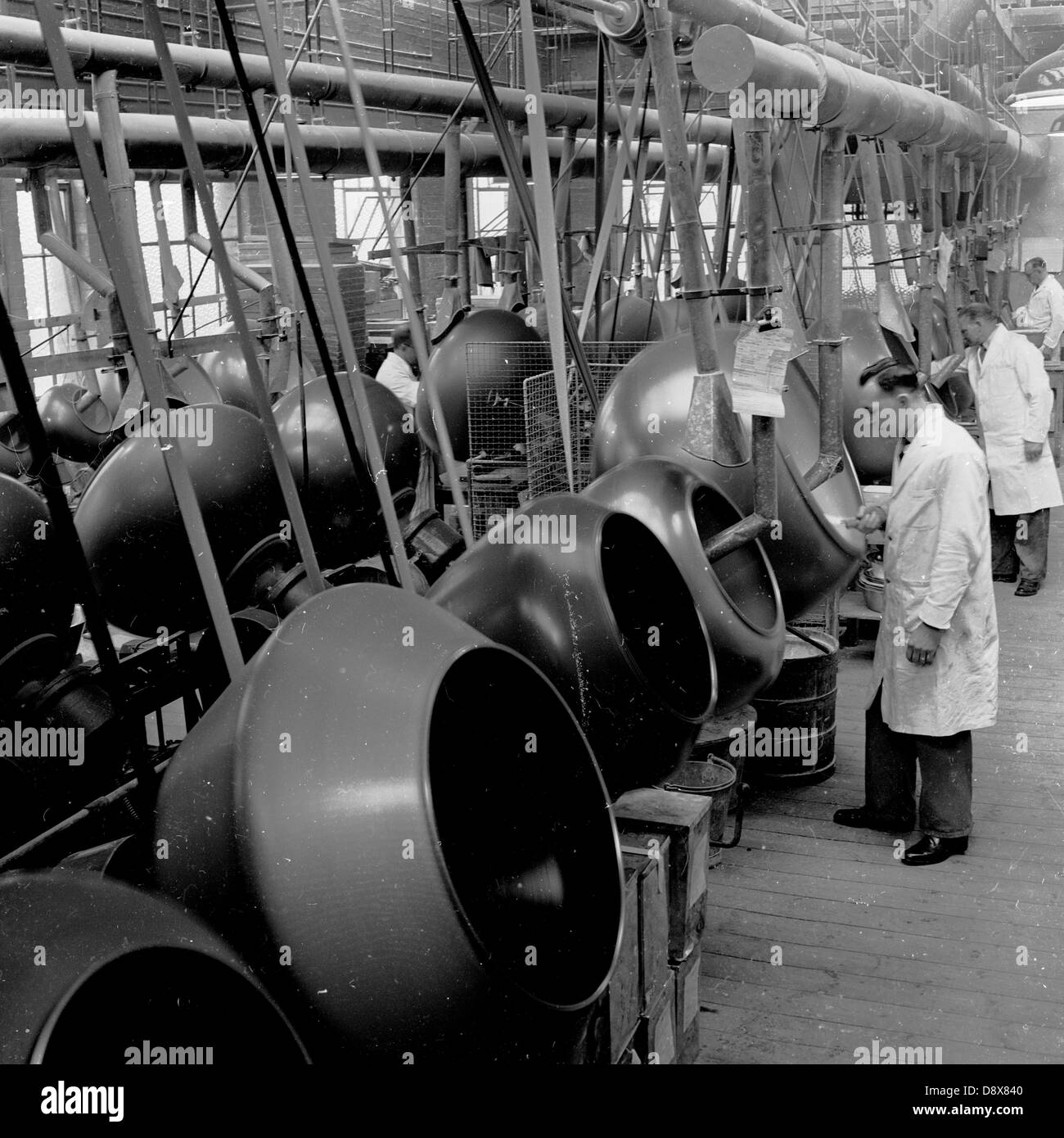 Historical 1950s. England. White coated male factory workers inspect ...