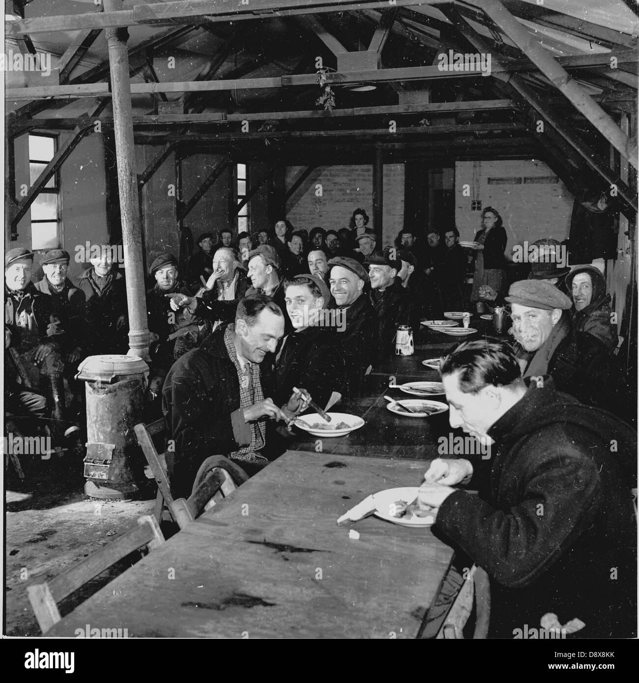 Historical 1950s. England. Group of workers or factory employees eat ...