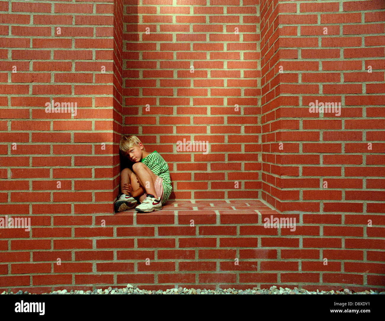 A boy sitting hunched up Stock Photo - Alamy