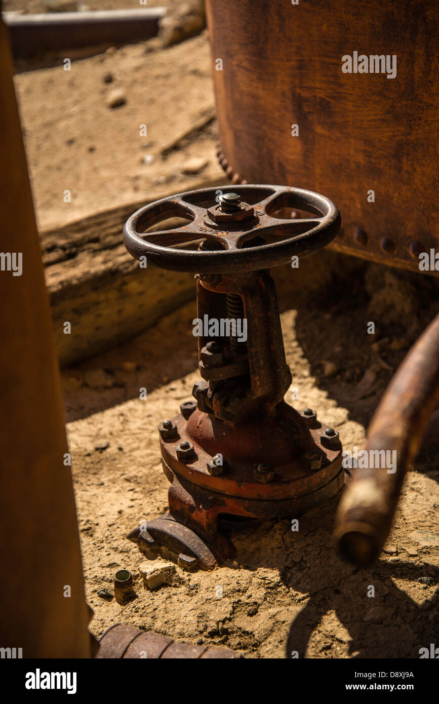 Rusty, half-buried valve assembly attached to settling tanks at a ...