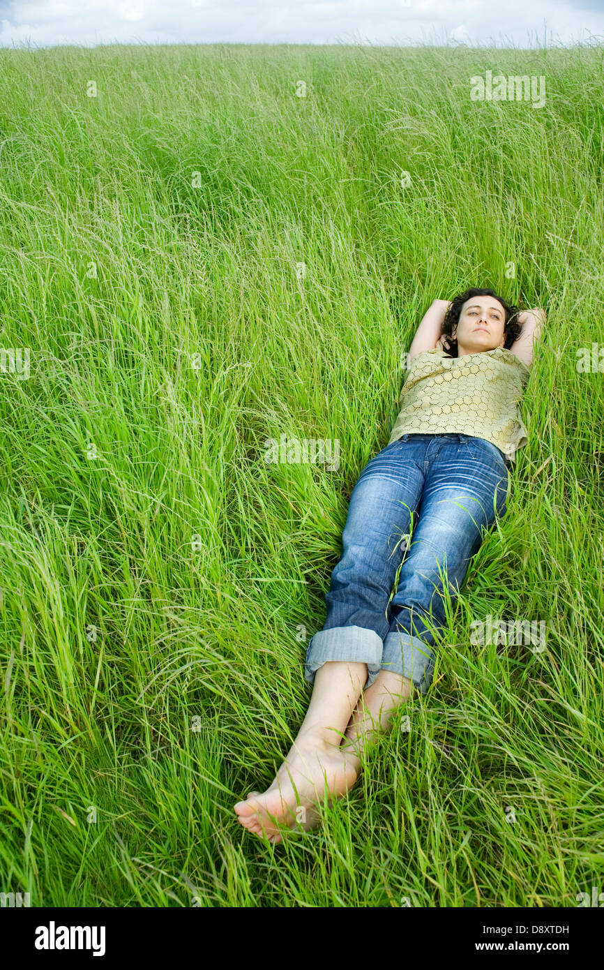 young barefooted woman resting on a peaceful field of grass Stock Photo ...