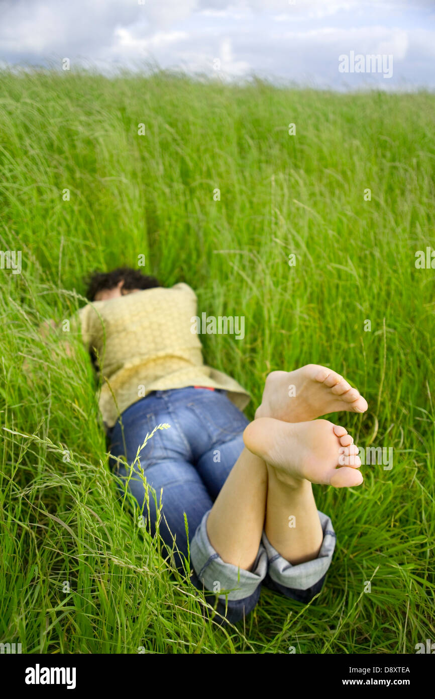 young barefooted woman resting on a peaceful field of grass Stock Photo ...