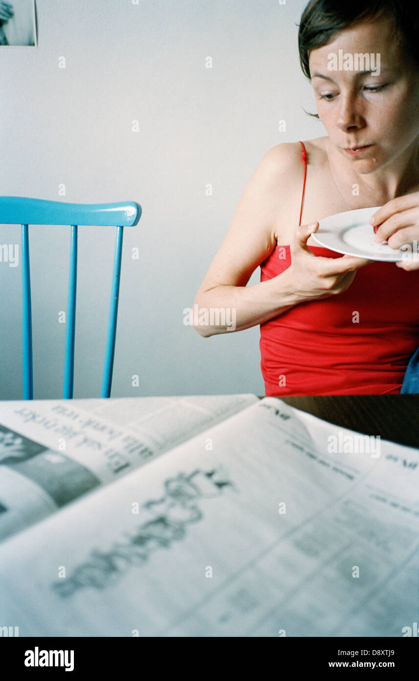 A woman reading the paper while eating, Sweden Stock Photo - Alamy