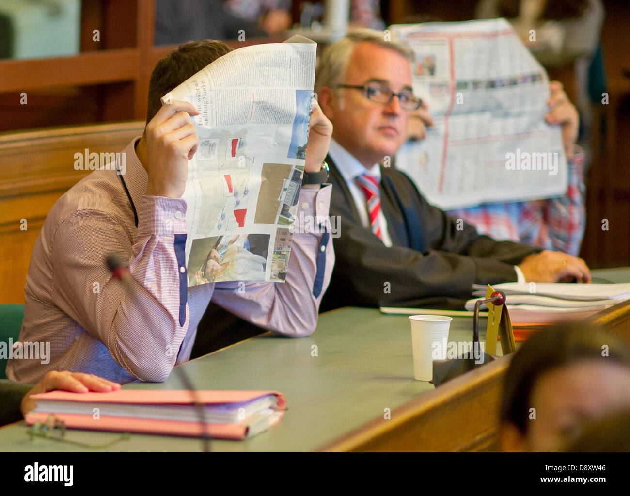 Defendants hide behind newspapers during the trial on the killing of ...