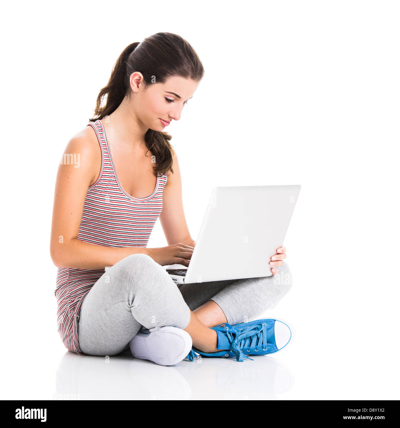 Beautiful student sitting in the floor with a laptop, isolated over a ...