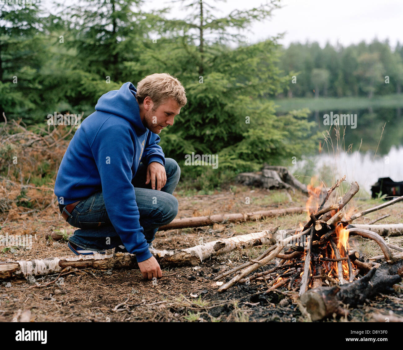A man by a bonfire in the forest Stock Photo - Alamy