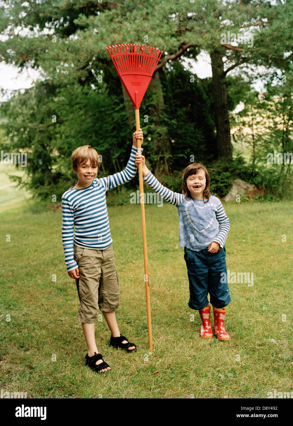 Two children holding a rake Stock Photo - Alamy