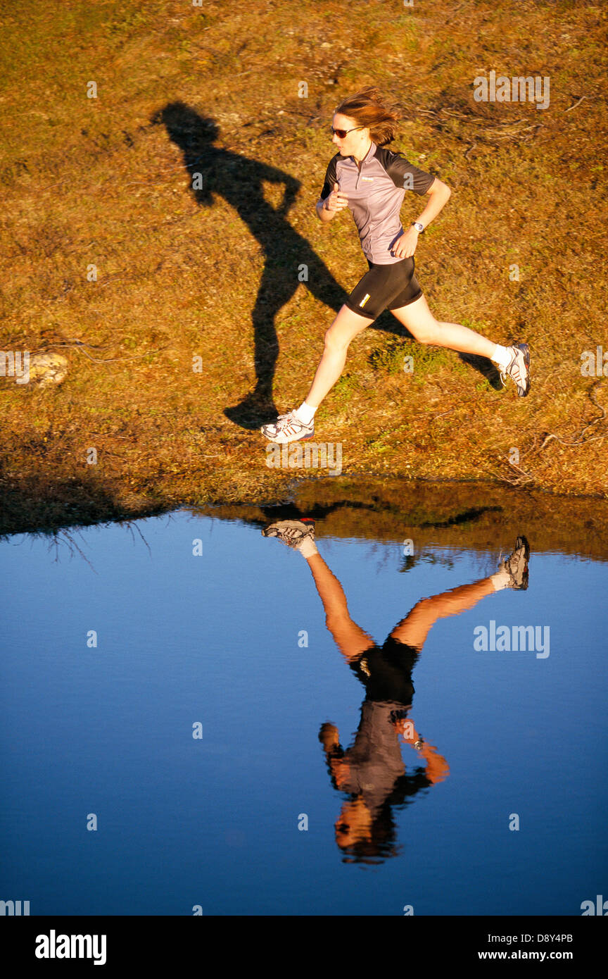 A woman jogging, her shadow and her reflection in water Stock Photo - Alamy