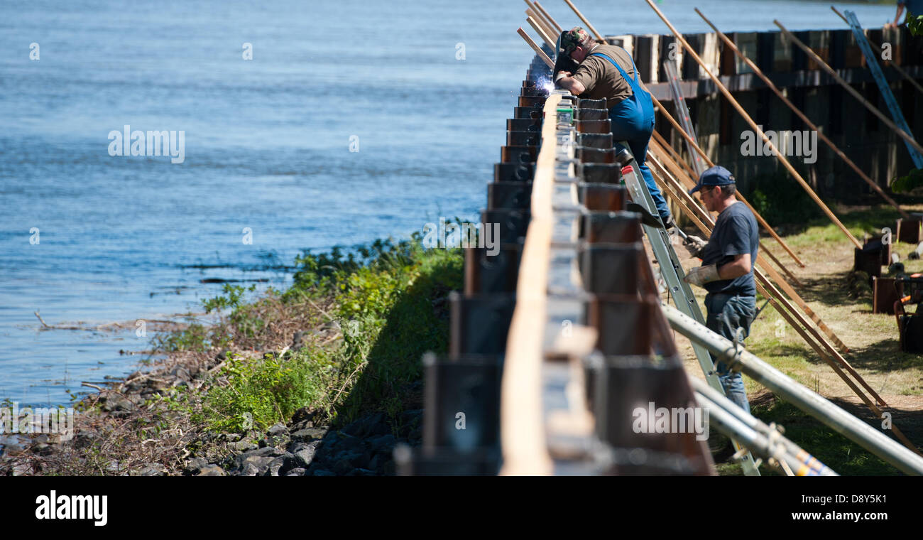 People build a temporary flood wall made from steel and wood near ...