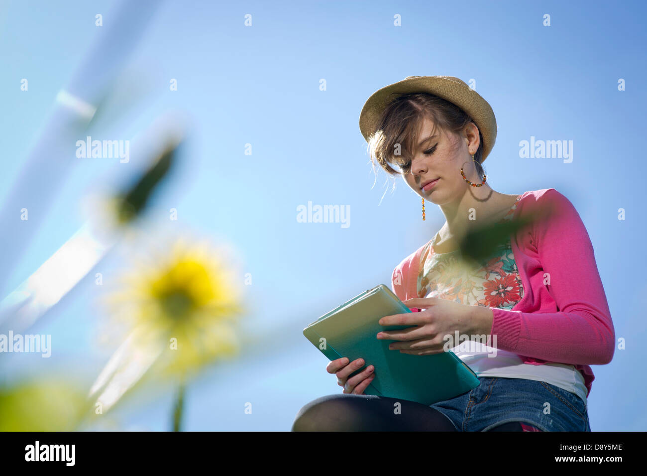 Teenage girl sitting on gate with ipad Stock Photo - Alamy