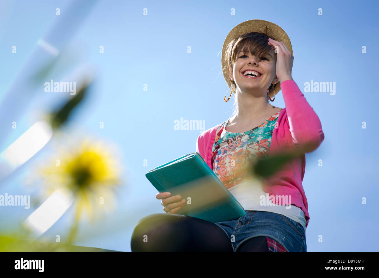 Teenage girl sitting on gate with ipad Stock Photo - Alamy