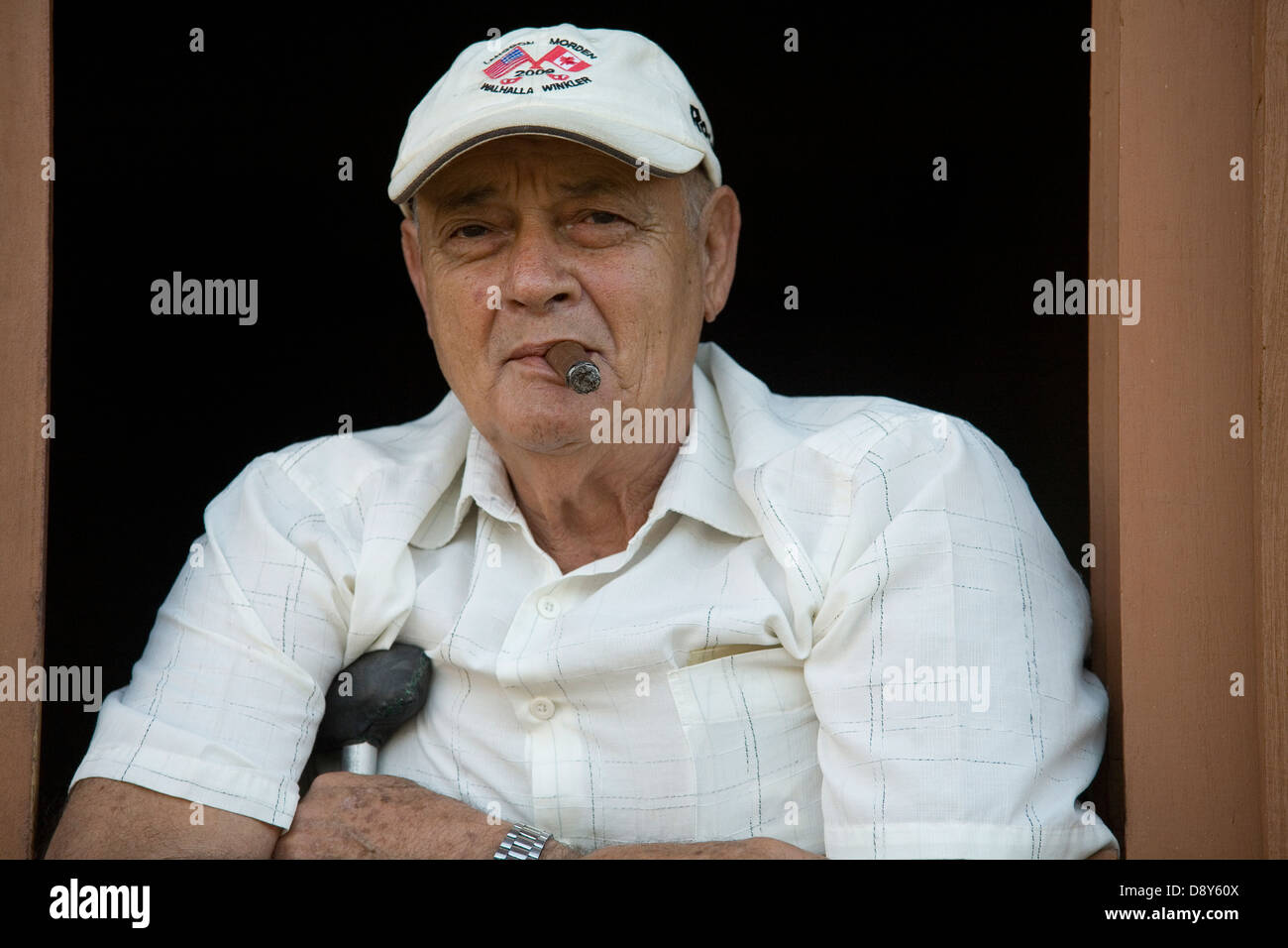 Cuban man having a morning cigar while leaning on his front stable door ...