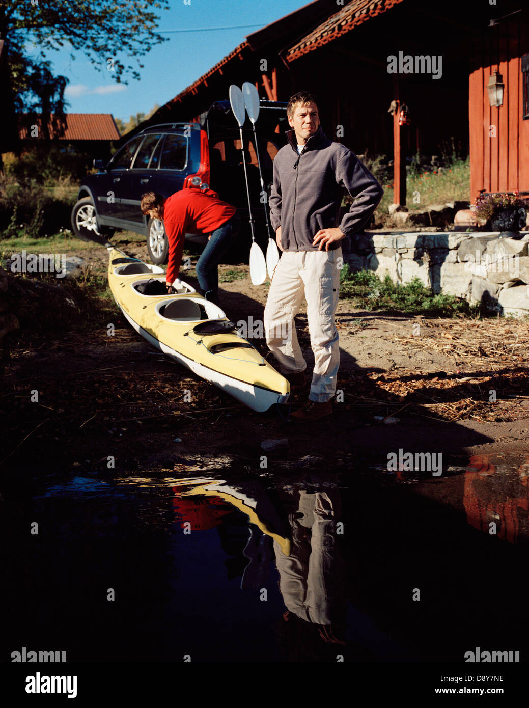 A man and a woman with a kayak on shore, Braviken, Sweden Stock Photo ...