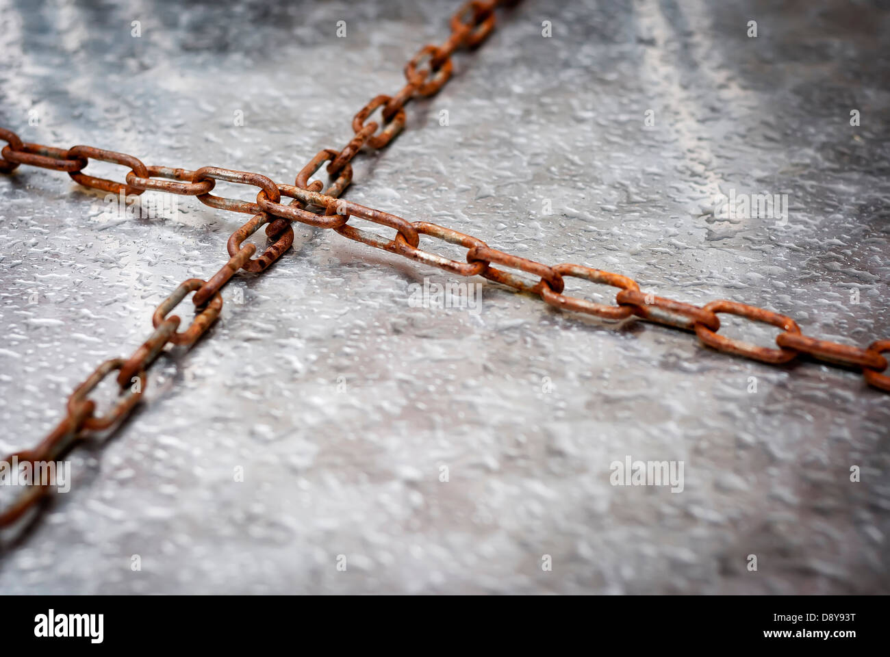 Crossed rusty chains on wet table Stock Photo - Alamy