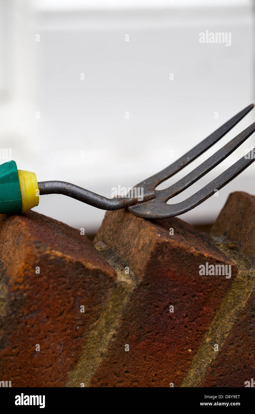 Gardening Fork on Brick wall Stock Photo - Alamy