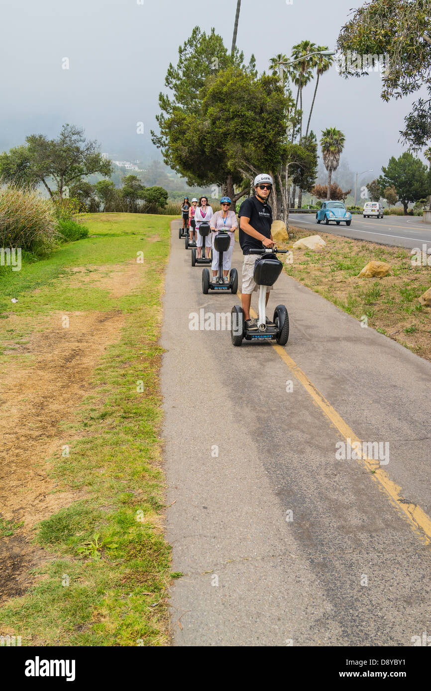 A group of Segway personal transporter riders wearing helmets drive ...