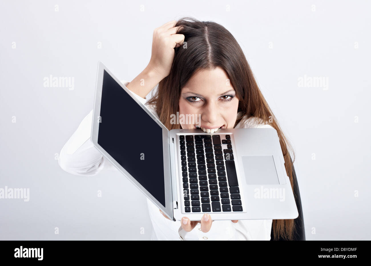 Frustrated businesswoman bite laptop over gray background Stock Photo ...