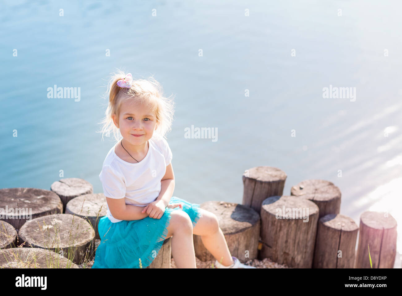 Cute little girl sitting near the lake in summertime in nature Stock ...