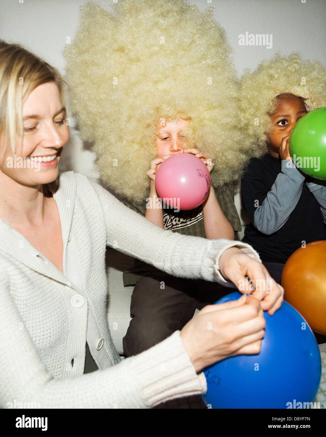 Children wearing wigs blowing balloons Stock Photo - Alamy
