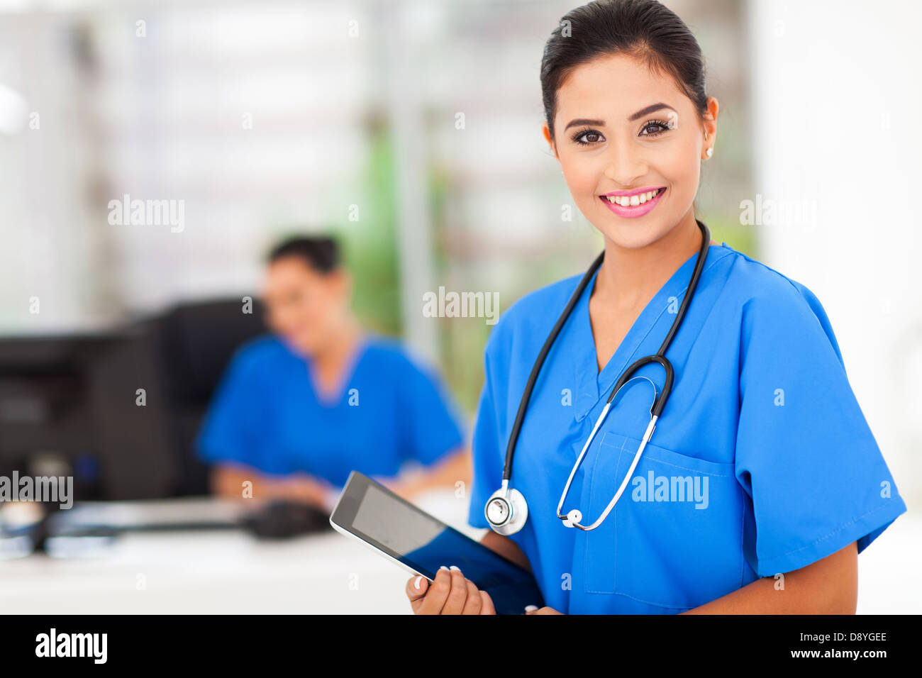 attractive young female nurse holding tablet computer at workplace ...