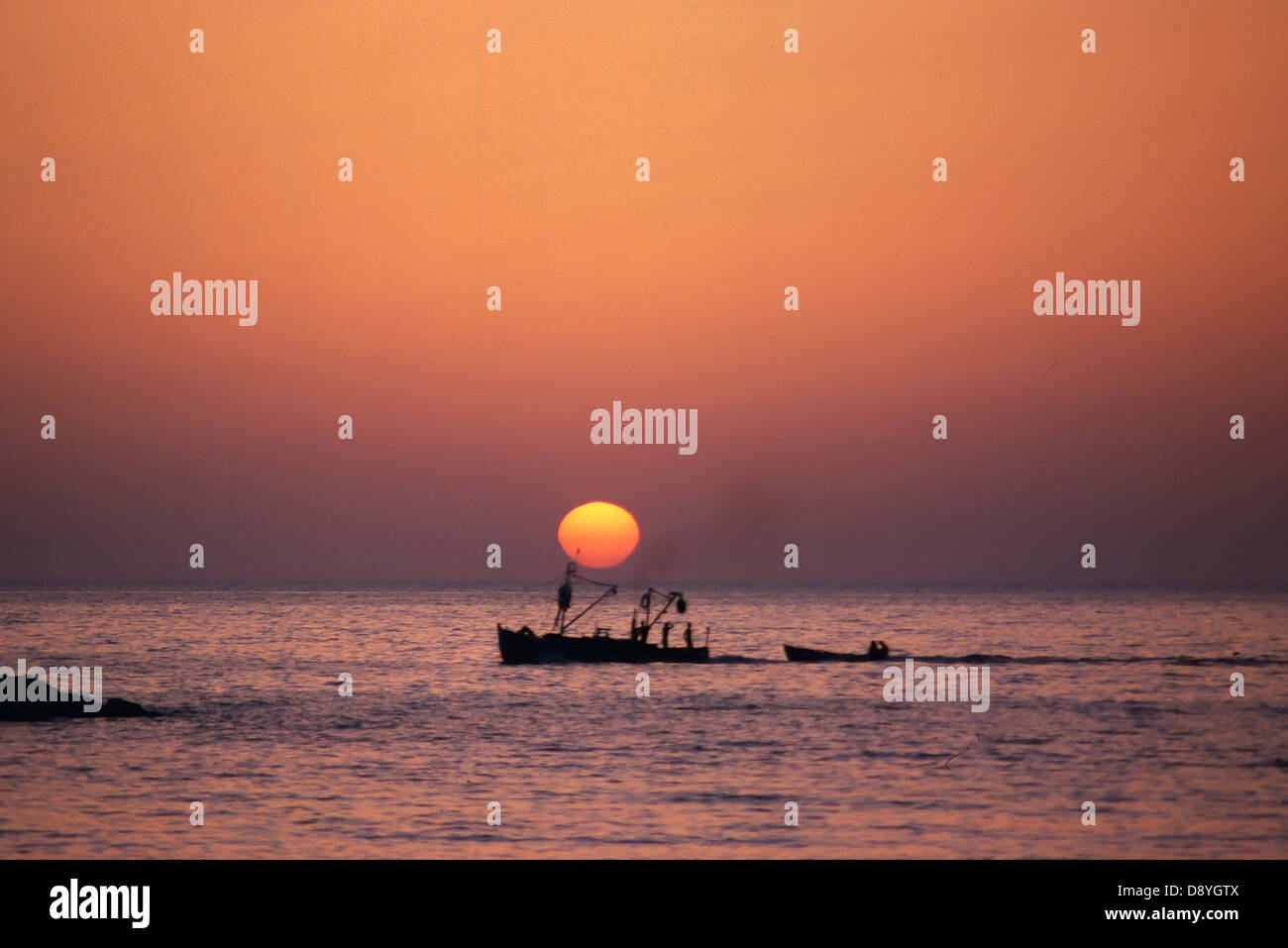 Fishing boat at sunset Stock Photo - Alamy