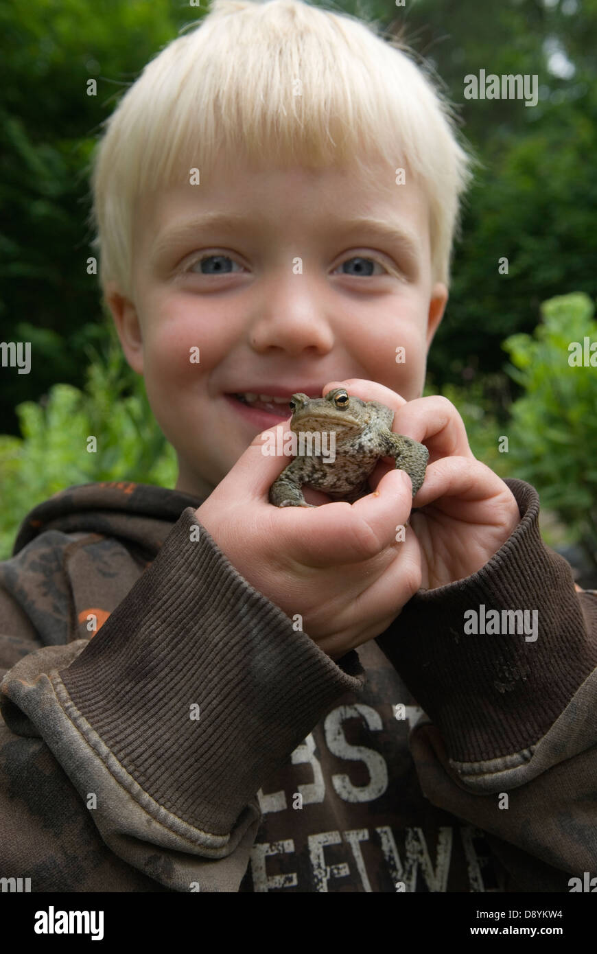 A blond boy holding a toad Stock Photo - Alamy