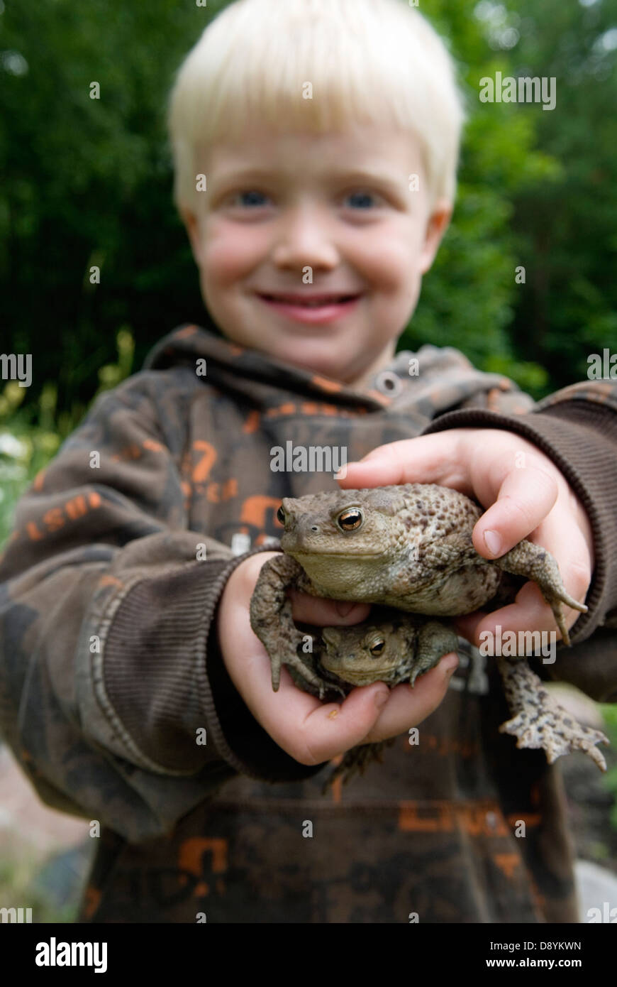 A blond boy holding toads Stock Photo - Alamy