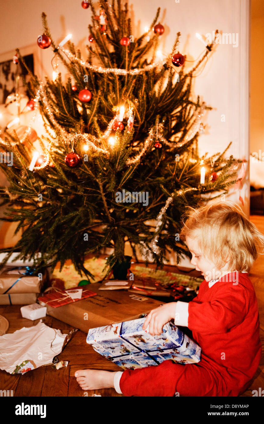 A boy sitting by a Christmas tree Stock Photo - Alamy
