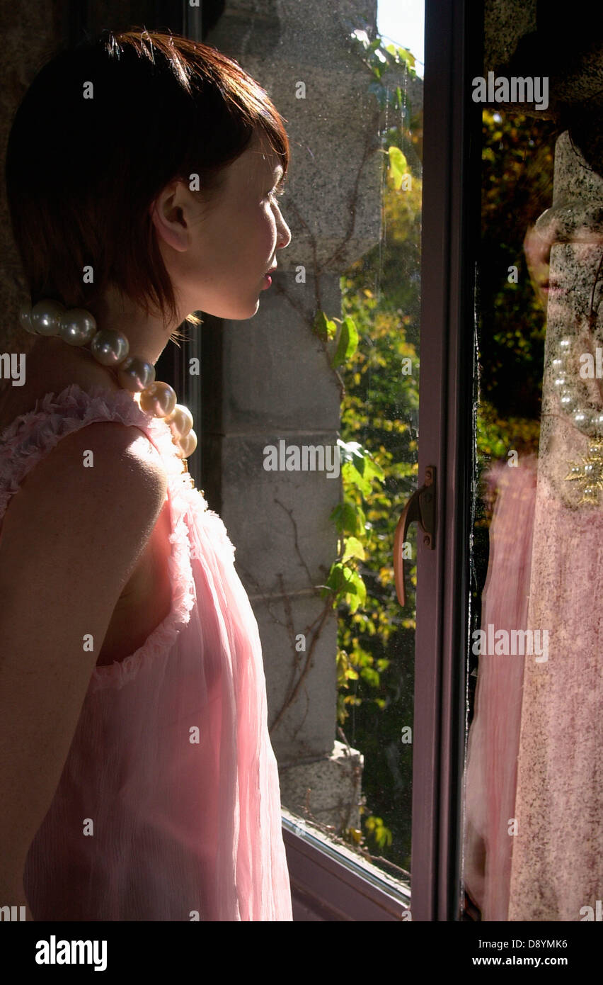 A woman watching out of a window Stock Photo - Alamy