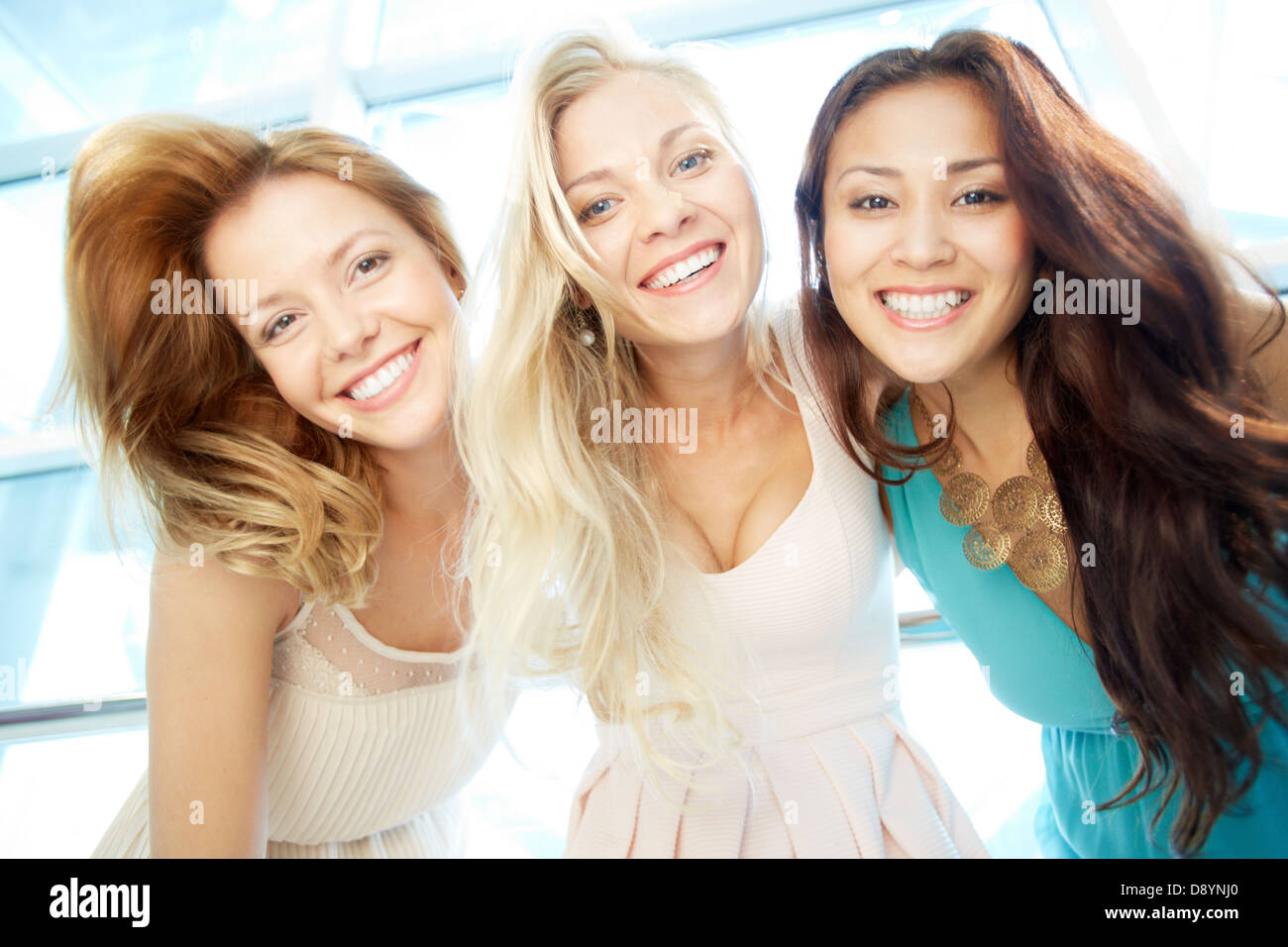Portrait of three elegant girls looking at camera with smiles Stock ...