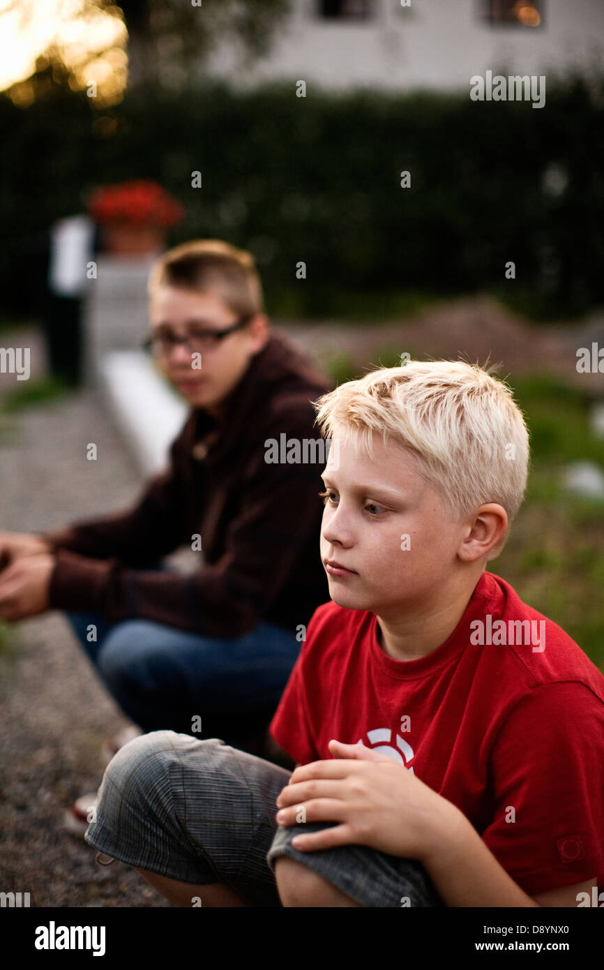 Boys sitting outside and looking away Stock Photo - Alamy