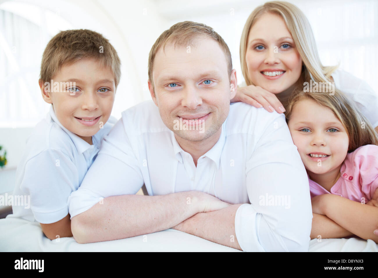 Portrait of happy parents with two children looking at camera at home ...