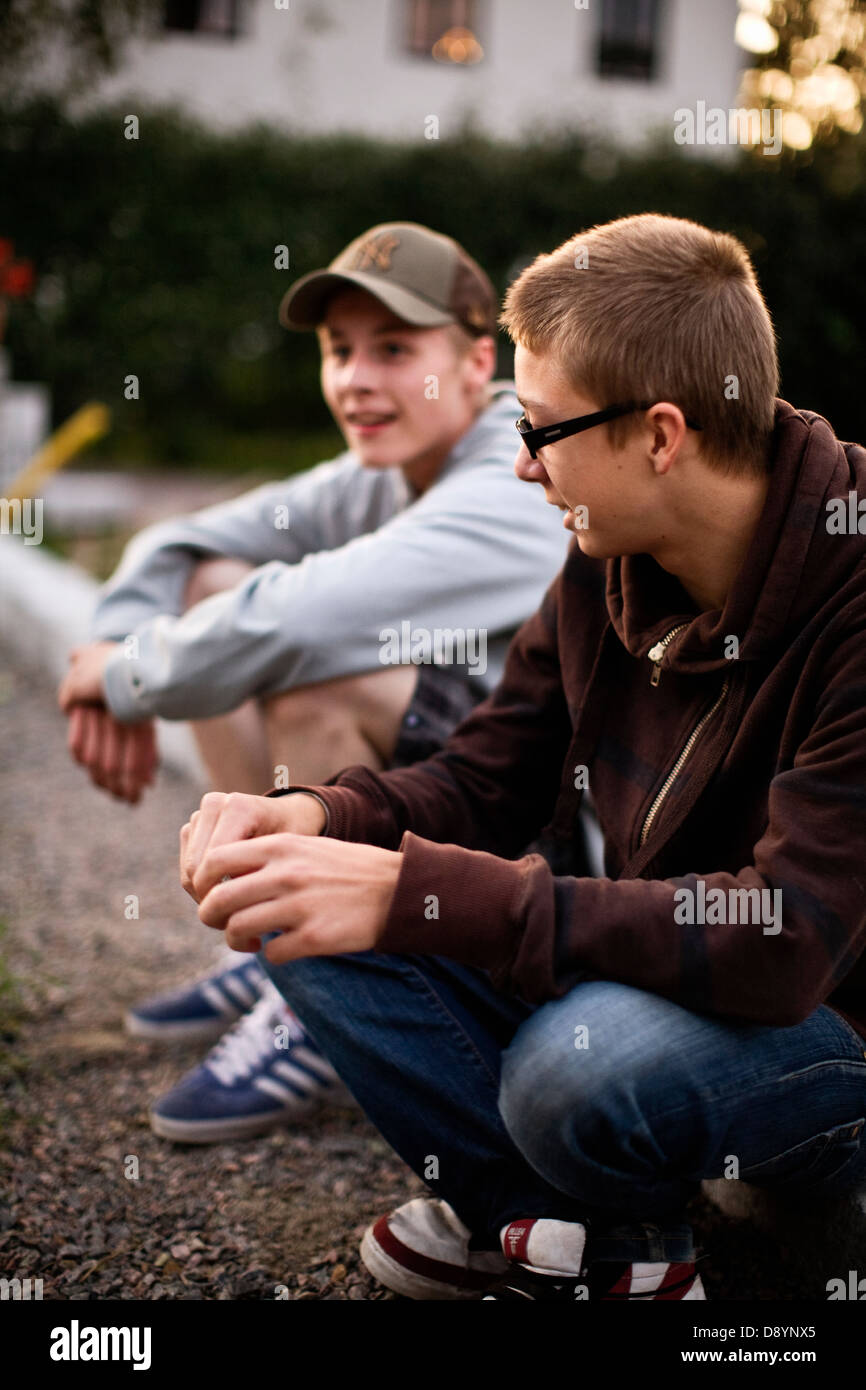 Teenagers sitting on curb Stock Photo - Alamy