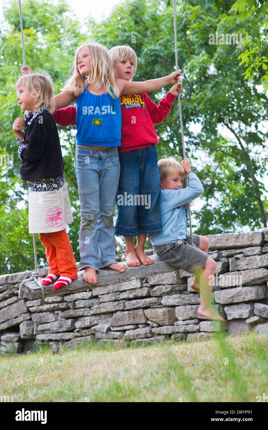 Four children on a swing Stock Photo - Alamy