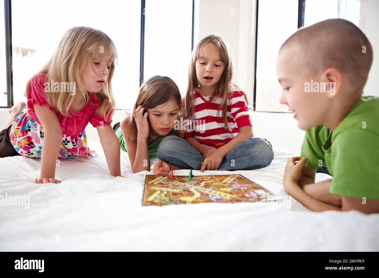 Children playing snakes and ladder on bed Stock Photo - Alamy