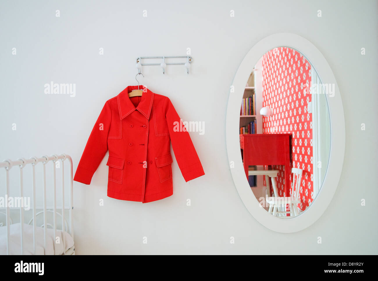 Red coat hanging by mirror on wall Stock Photo - Alamy