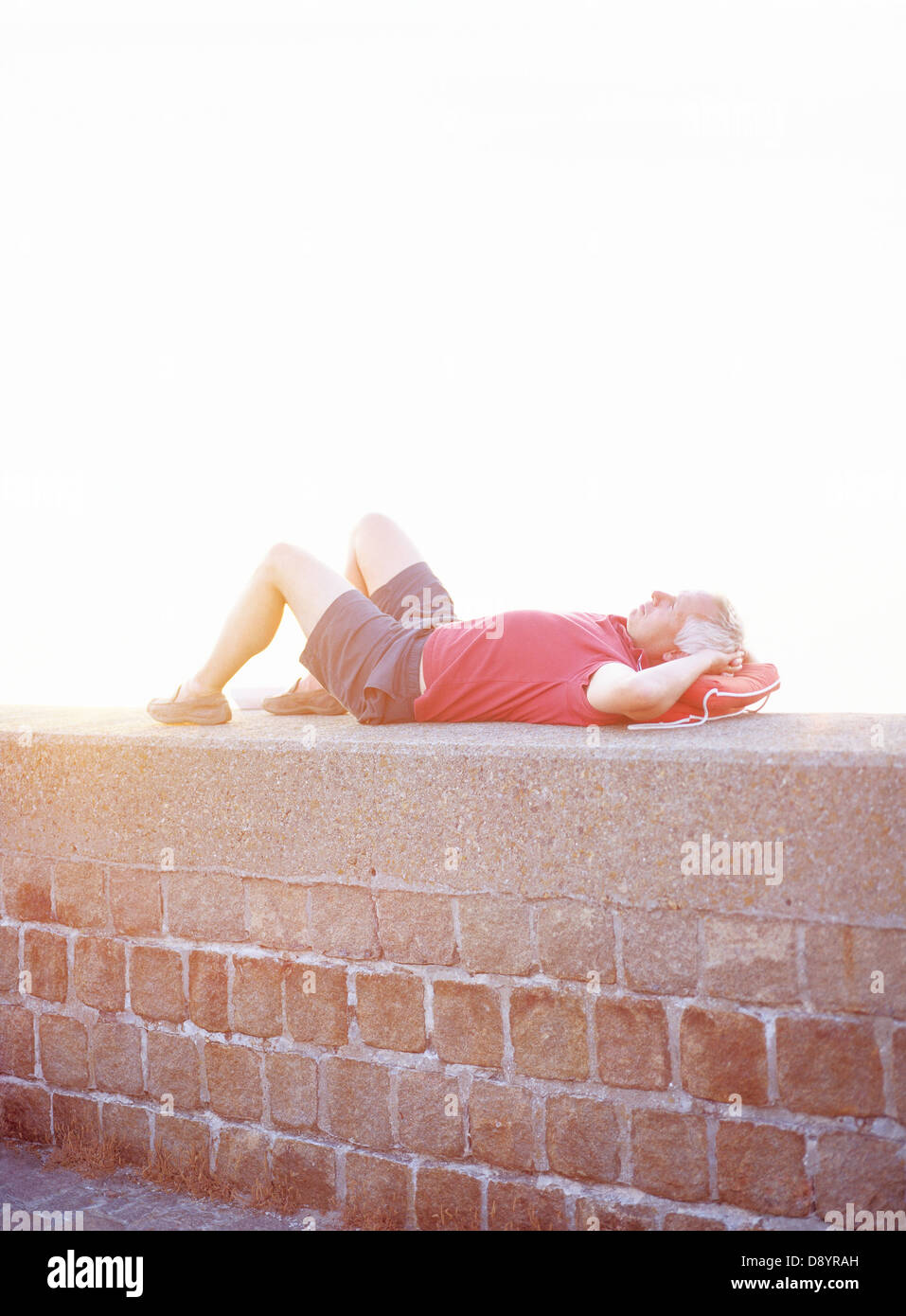 A man resting on a stone wall Stock Photo - Alamy