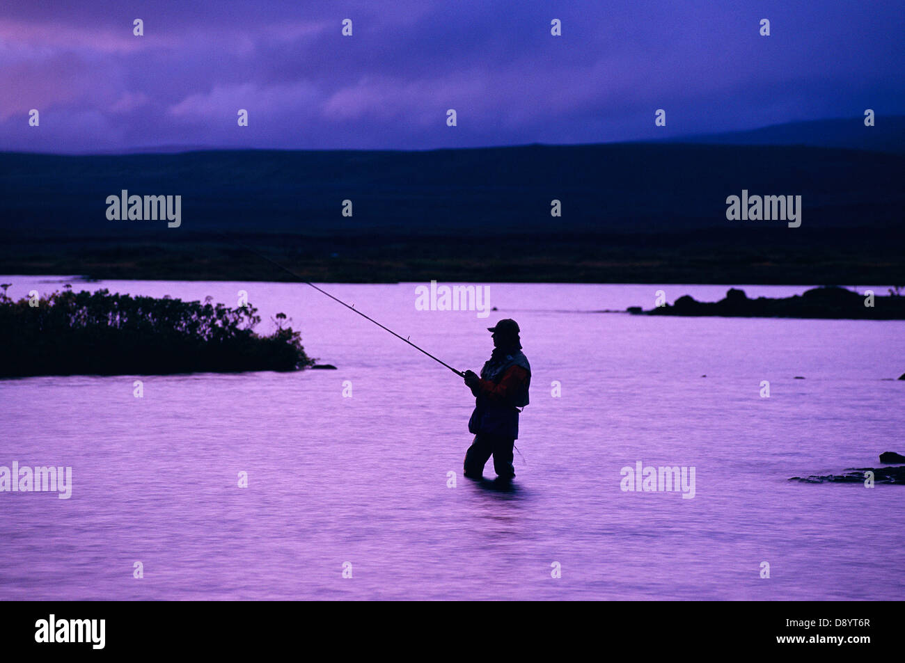 A fisherman standing in the water fishing Stock Photo - Alamy